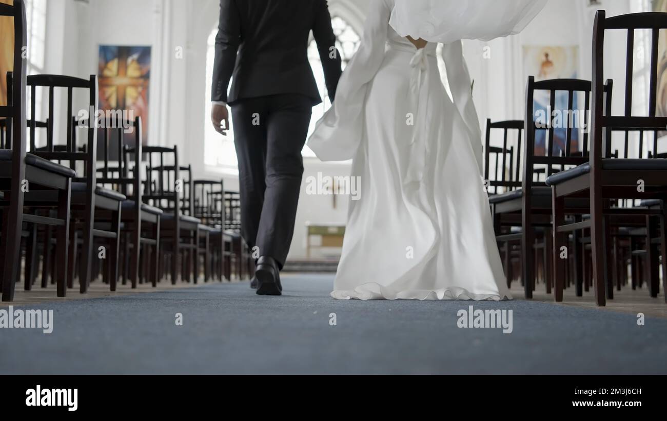 Beautiful newlyweds walking down aisle. Action. Rear view of couple of ...