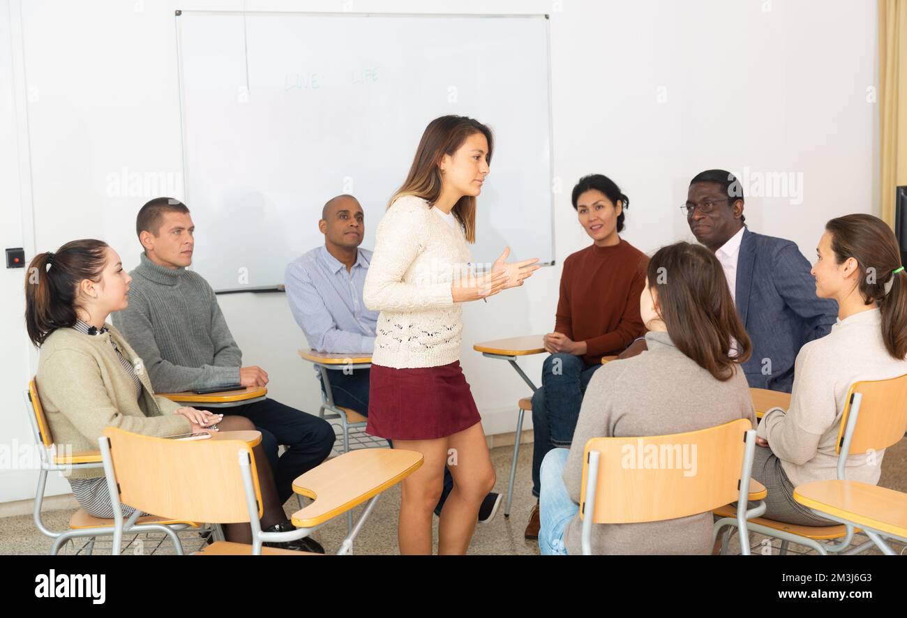 Group of students attentively listening to lecture of female teacher ...