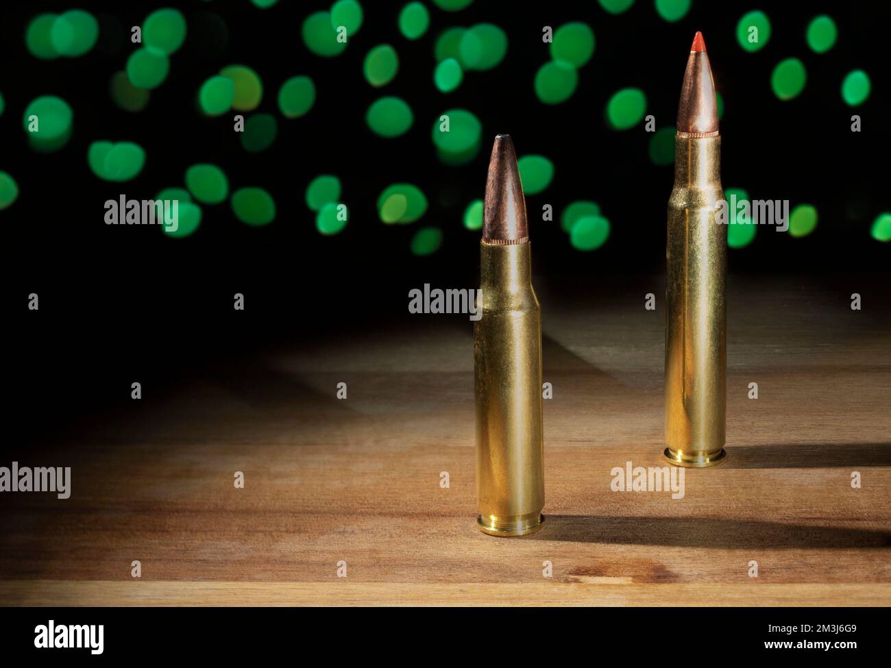 Thirty caliber bullets on a wood table with green Chrisimas lights ...