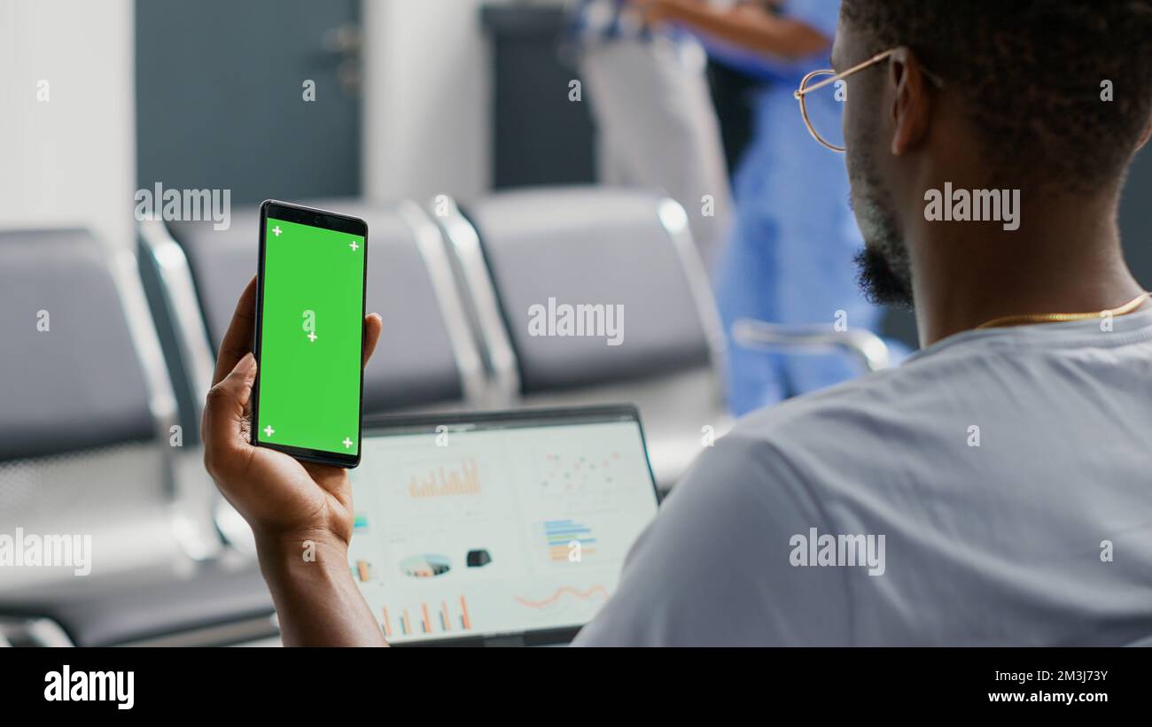 Male patient using greenscreen template on smartphone while he waits in ...