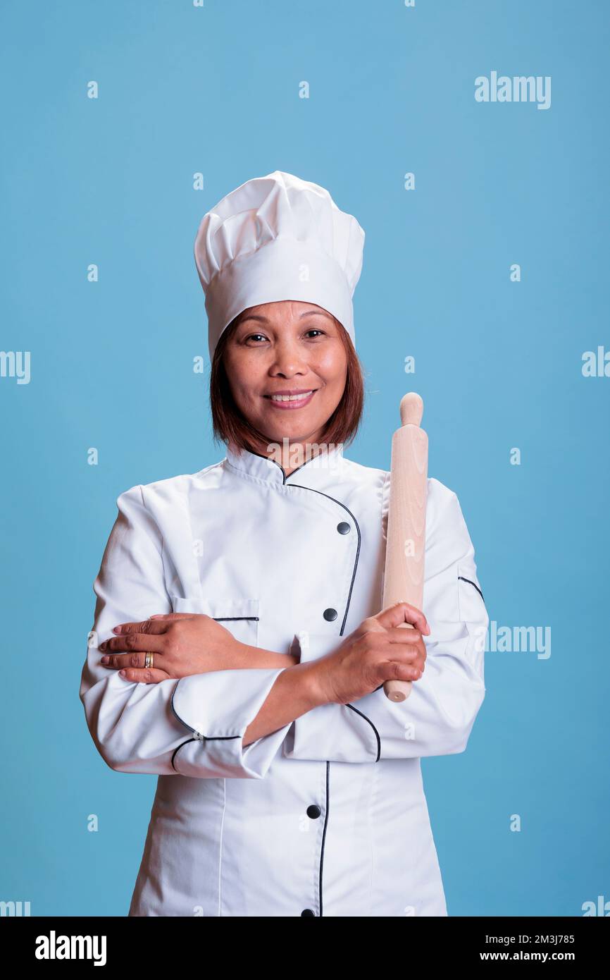 Professional positive asian cook standing with arm crossed holding ...