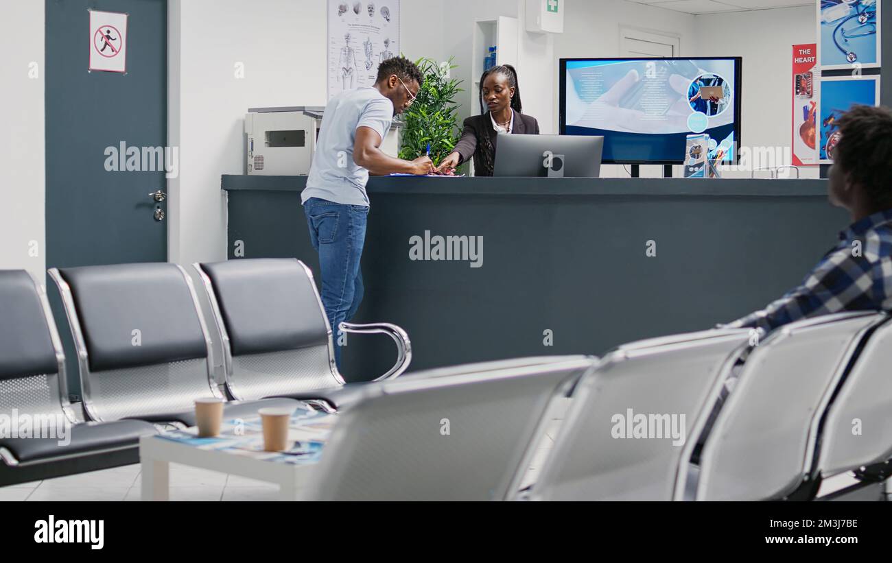 Young adult filling in checkup report papers at reception counter ...