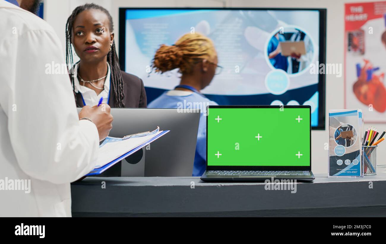 People working with greenscreen display on laptop in facility lobby ...