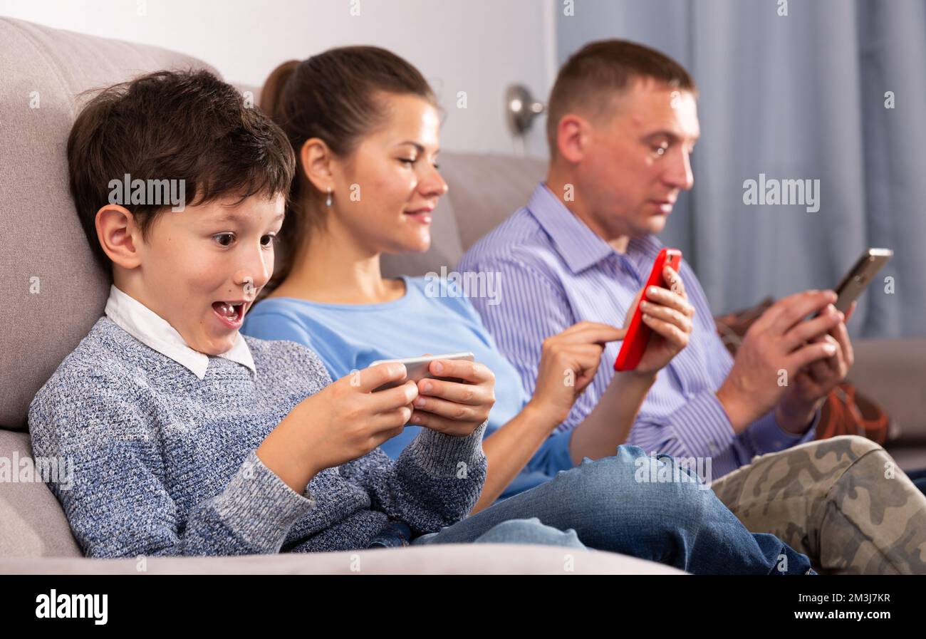 Boy and his parents using phones Stock Photo - Alamy