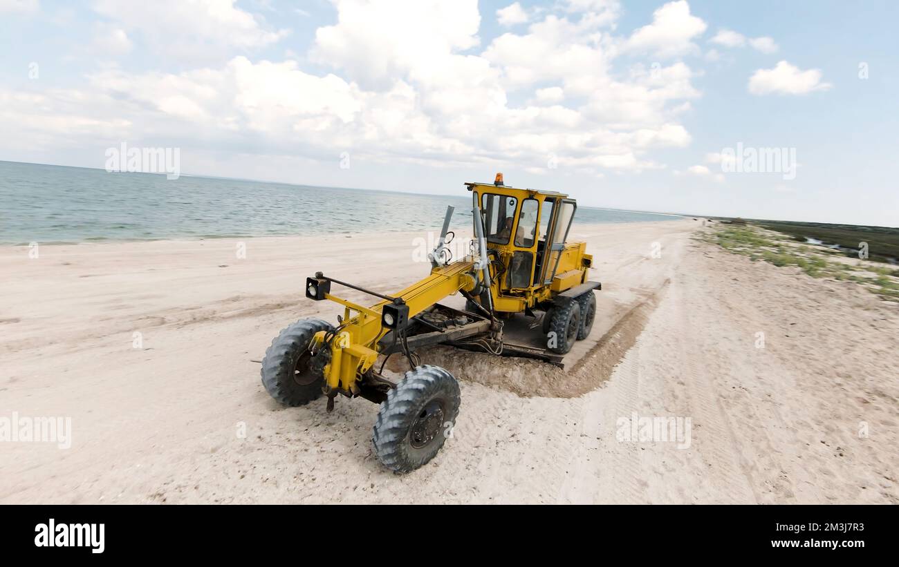 Yellow tractor. Shot . A large tractor working on the ocean shore ...