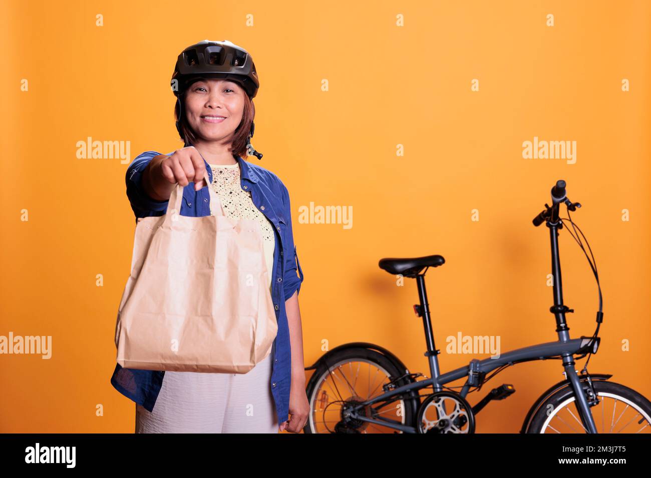 Smiling restaurant delivery worker wearing helmet while delivering ...