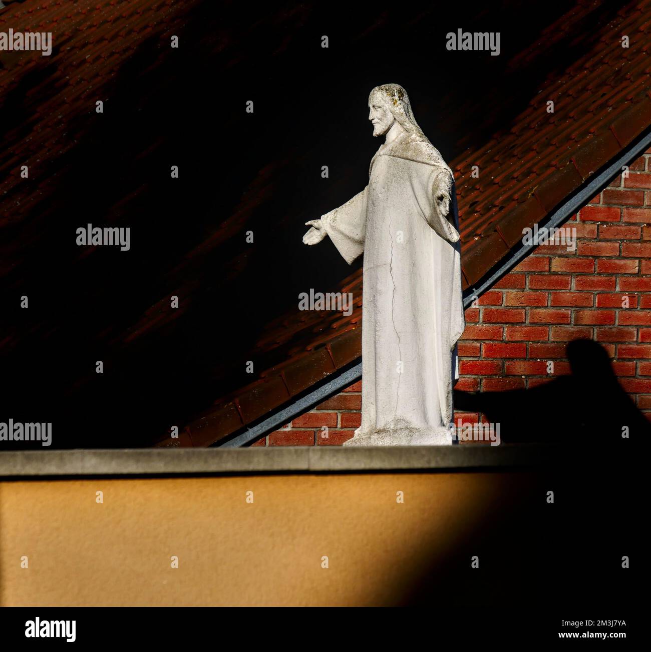 The sunlight falling on the statue of Jesus Christ with brick walls in ...