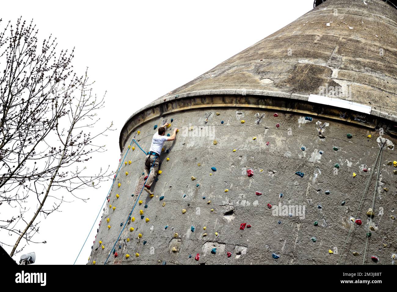 A low-angle shot of a person rock climbing on a tower strapped with ...