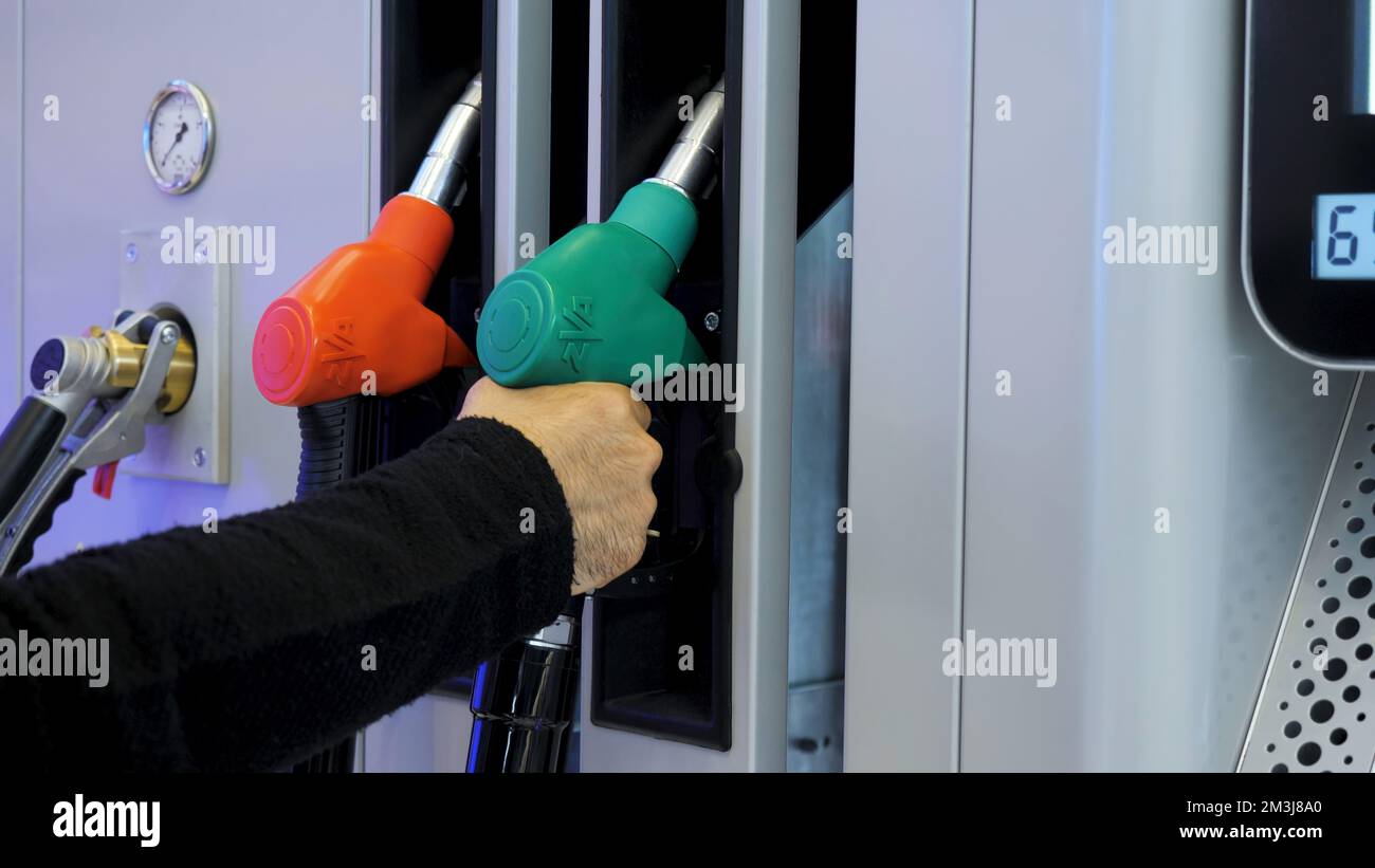 Close-up of hose at gas station. Media. Man takes refueling hose gun ...