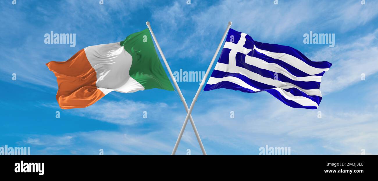 two crossed flags Greece and Ireland waving in wind at cloudy sky ...