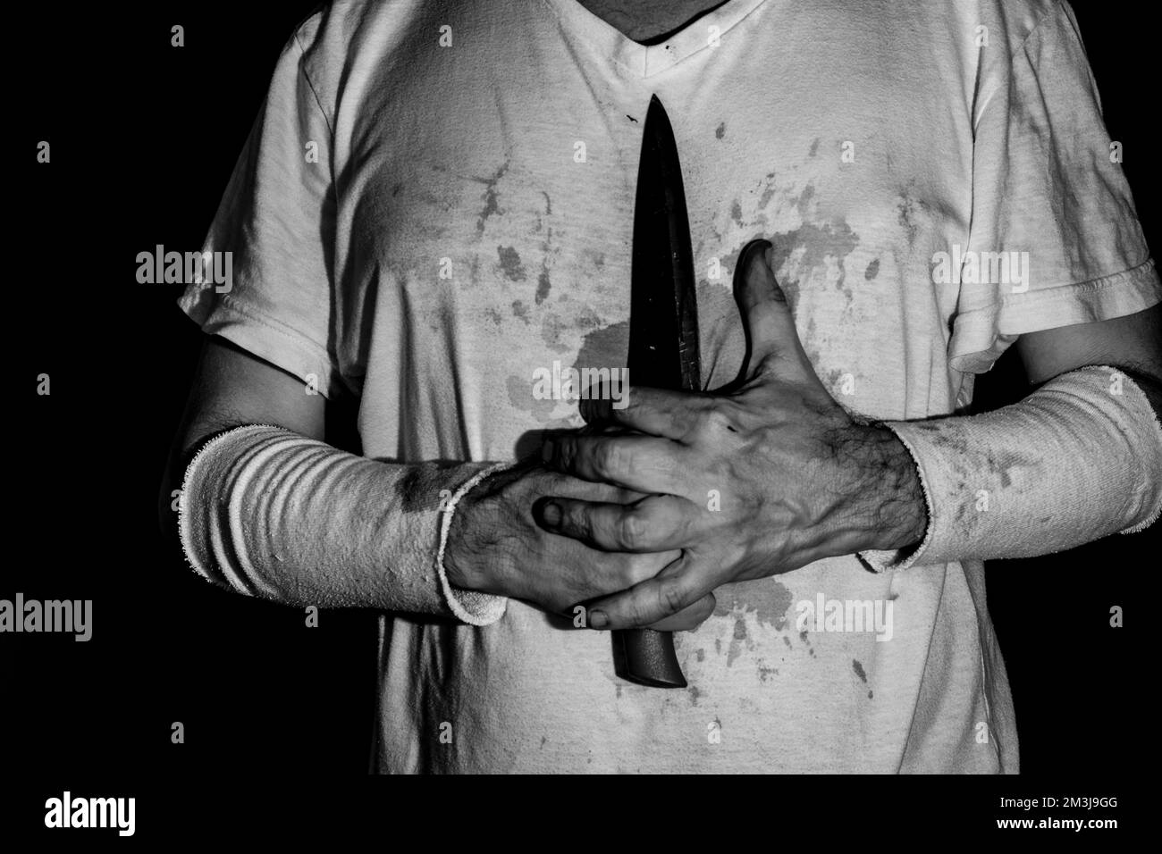 Black and white portrait of a man holding a knife against his chest ...