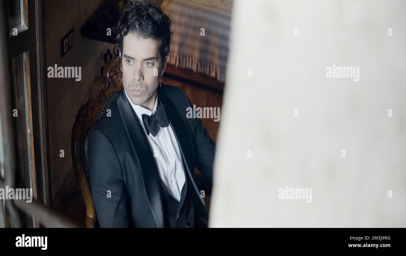 Man with black curly hair sitting and looking confident. Action. Young ...