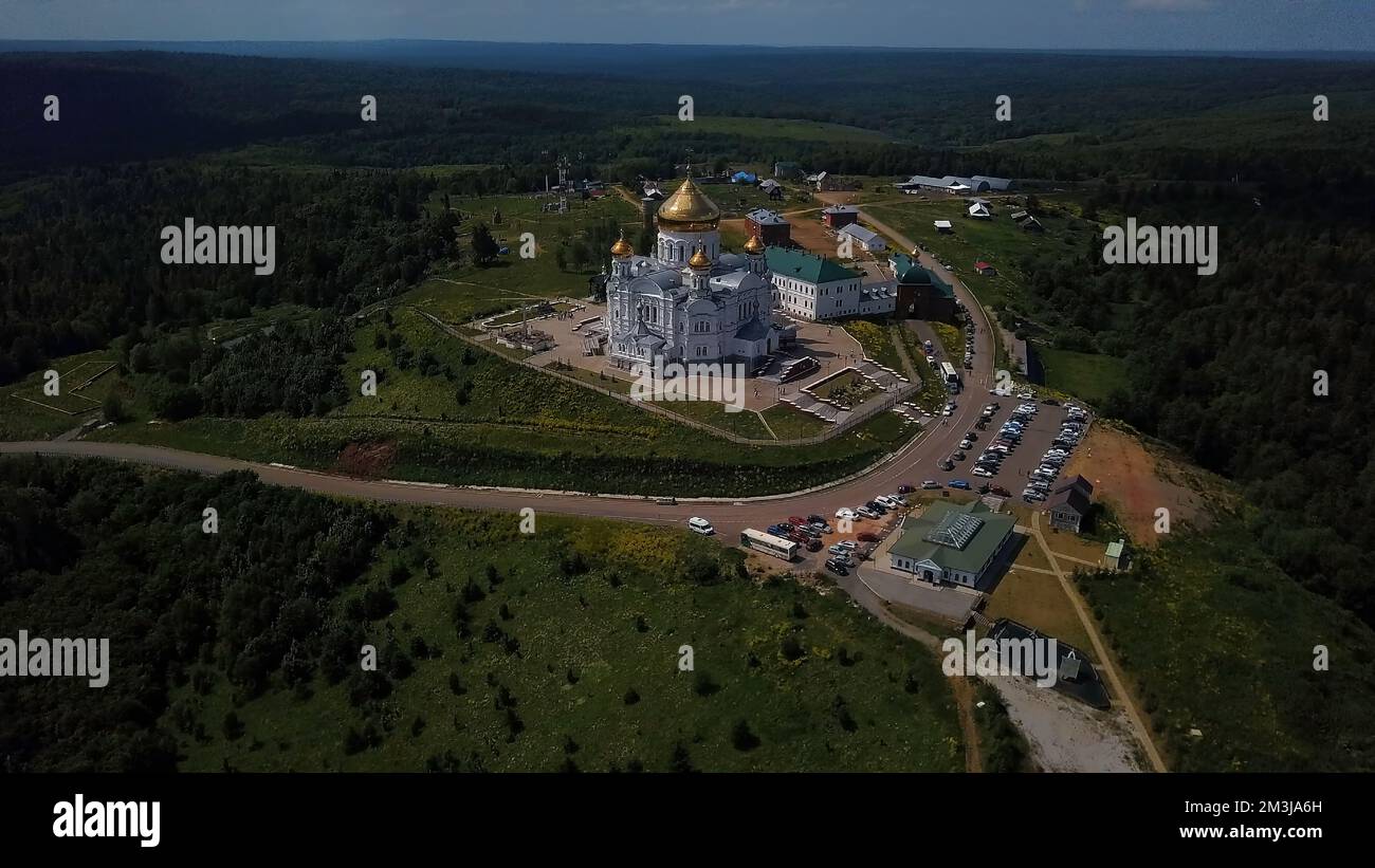 Aerial view of a white church with golden domes. Clip. Green valley and ...