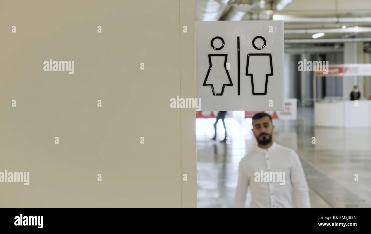 Young man walking inside the public bathroom inside shopping mall. HDR ...