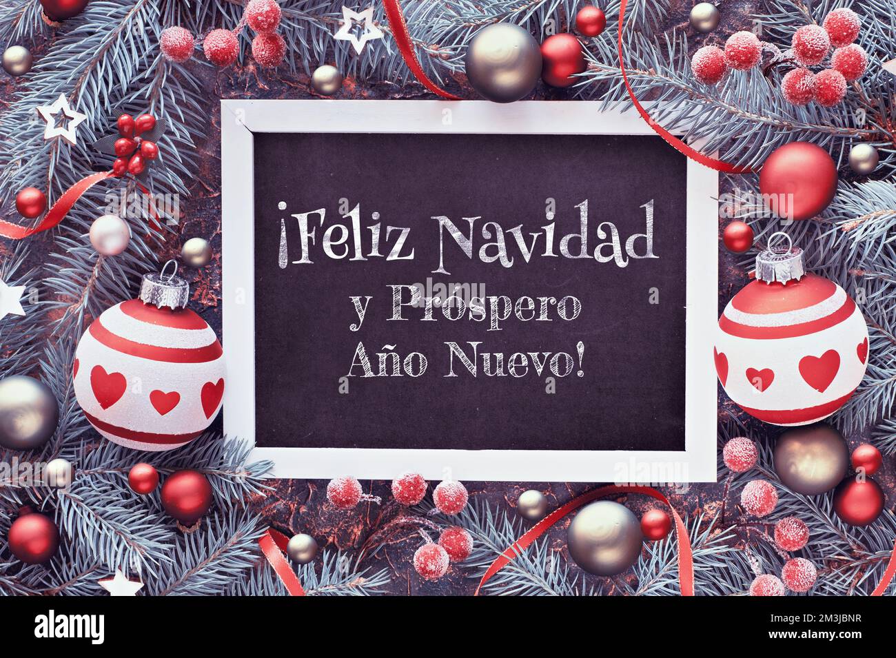 Fir twig decorated with baubles, berries and stars, black-board. Feliz ...