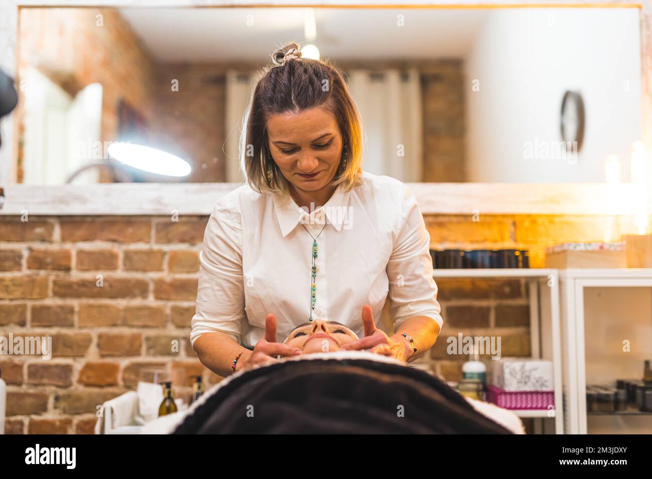 Professional beautician doing a facial skin massage to a woman in a spa ...