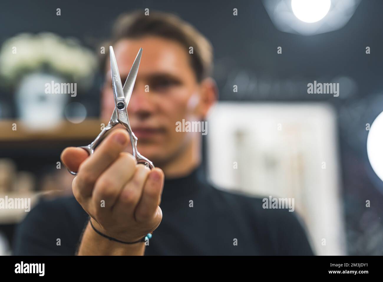 Blurred hairdresser man holding scissors in front of his face. High ...