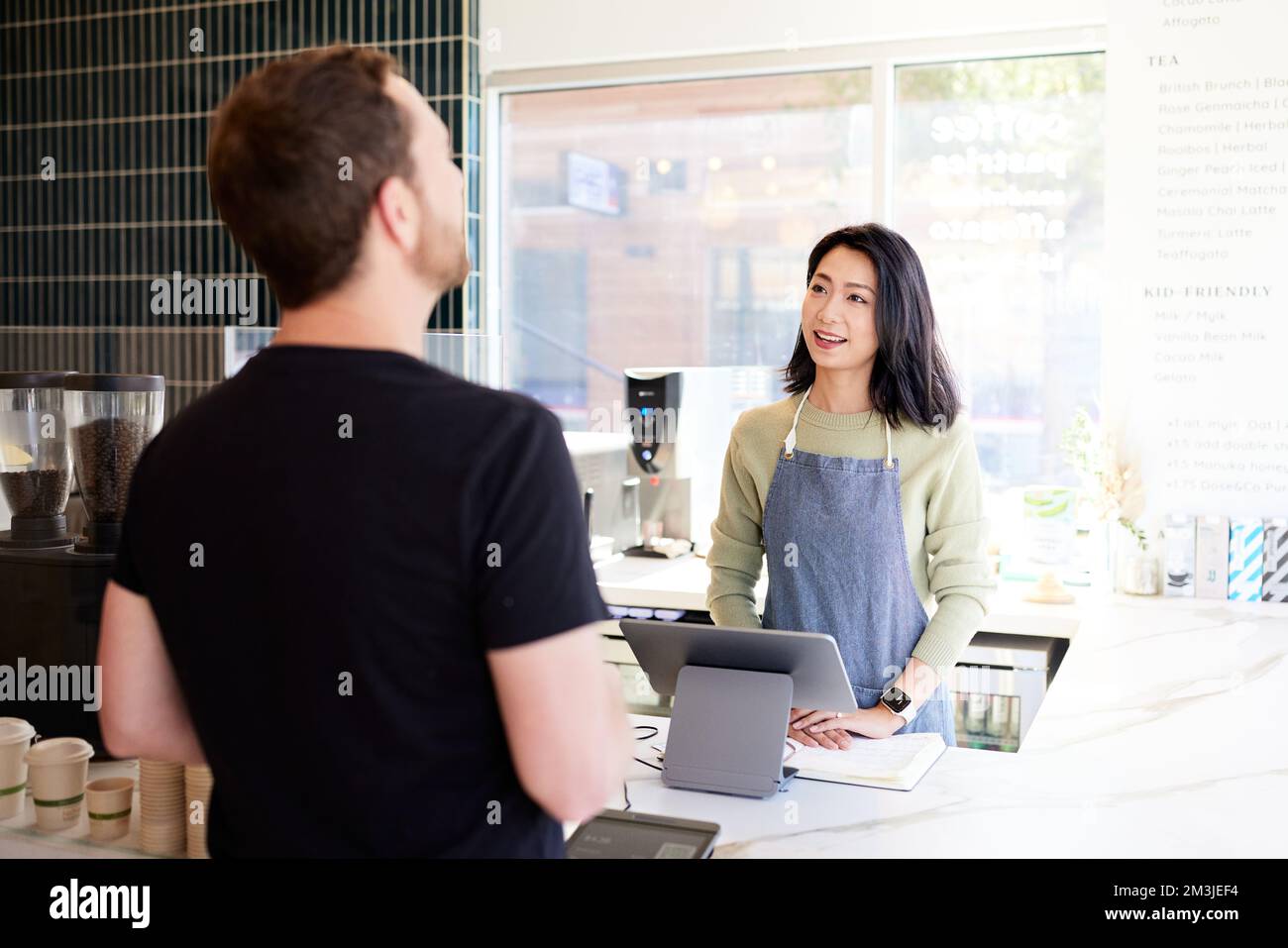 Smiling cashier talking with male customer in coffee shop Stock Photo ...