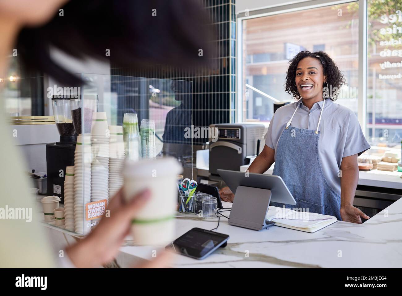 Happy female cashier looking at customer from checkout counter Stock ...