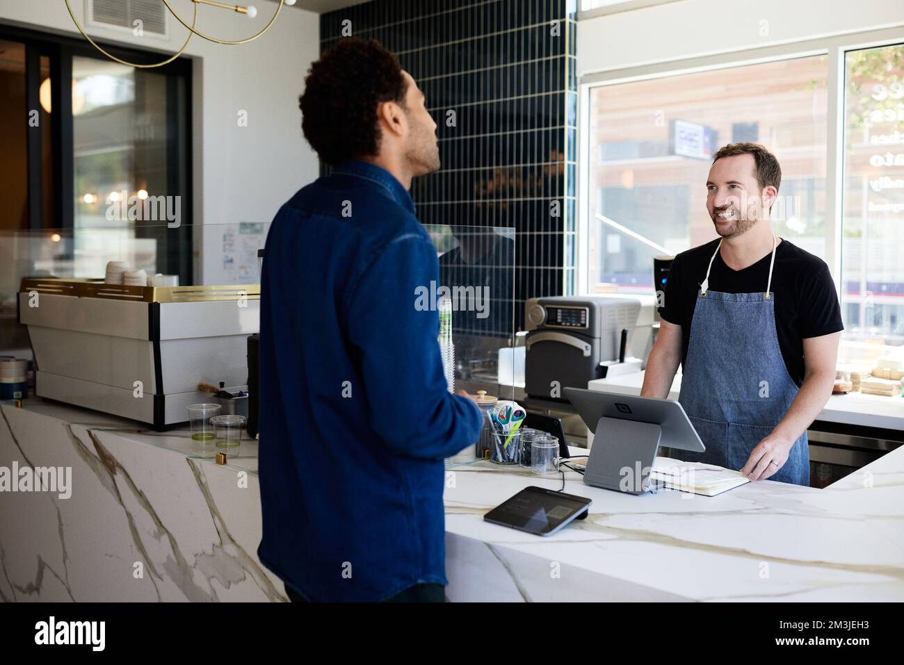 Smiling male owner talking to customer in coffee shop Stock Photo - Alamy