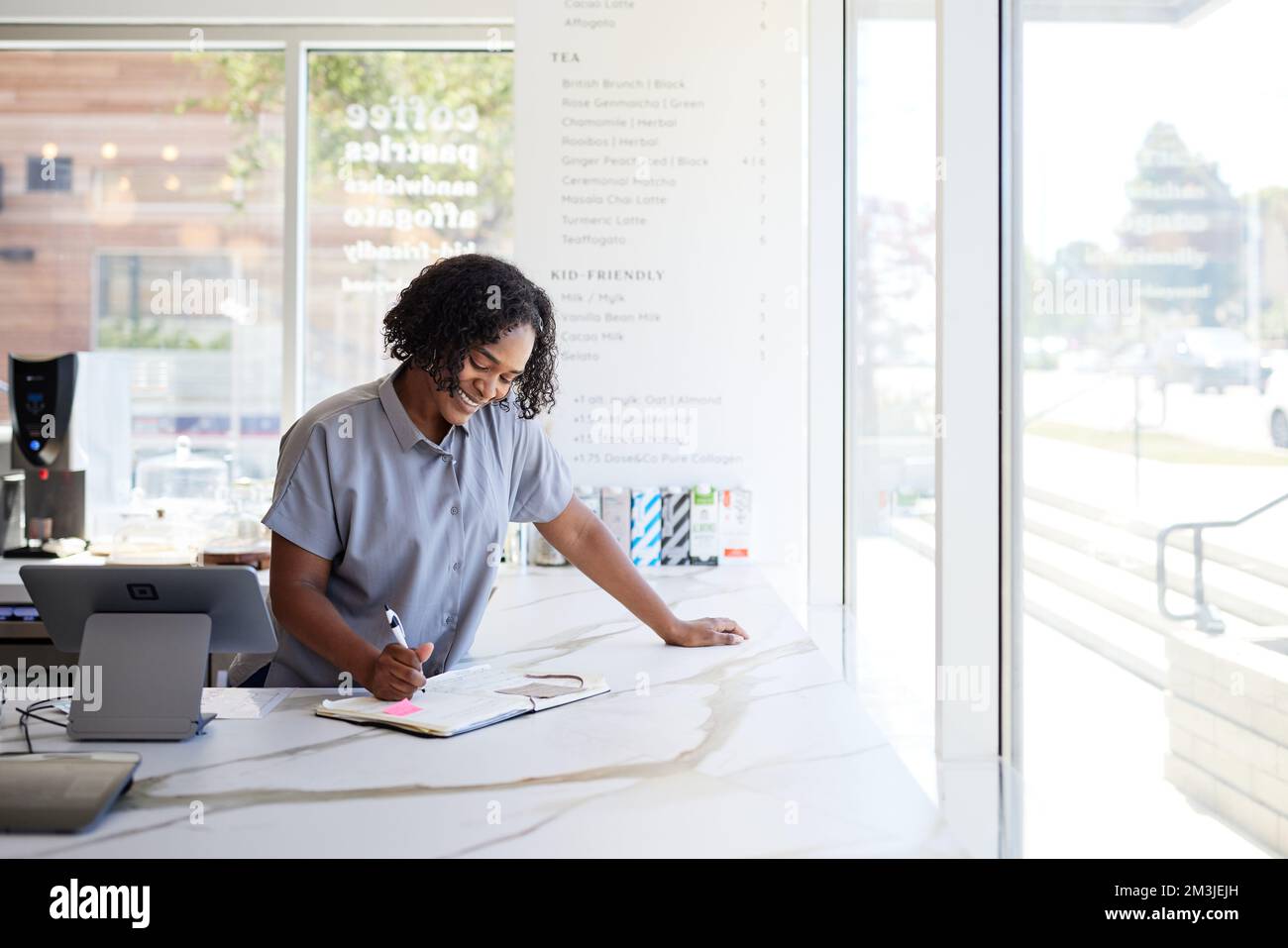 Smiling female entrepreneur accounting on checkout counter Stock Photo ...