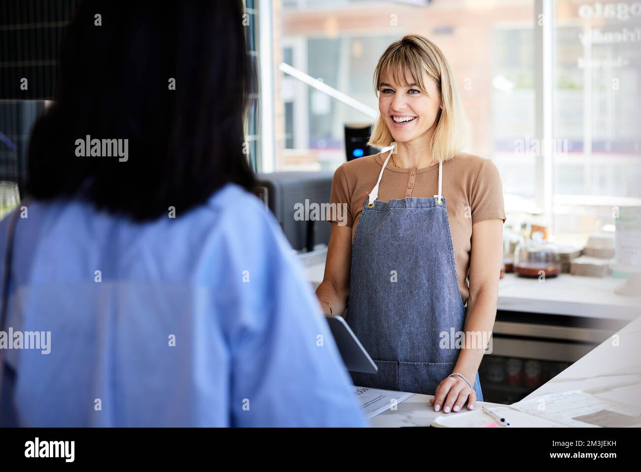 Smiling saleswoman talking to female customer in coffee shop Stock ...