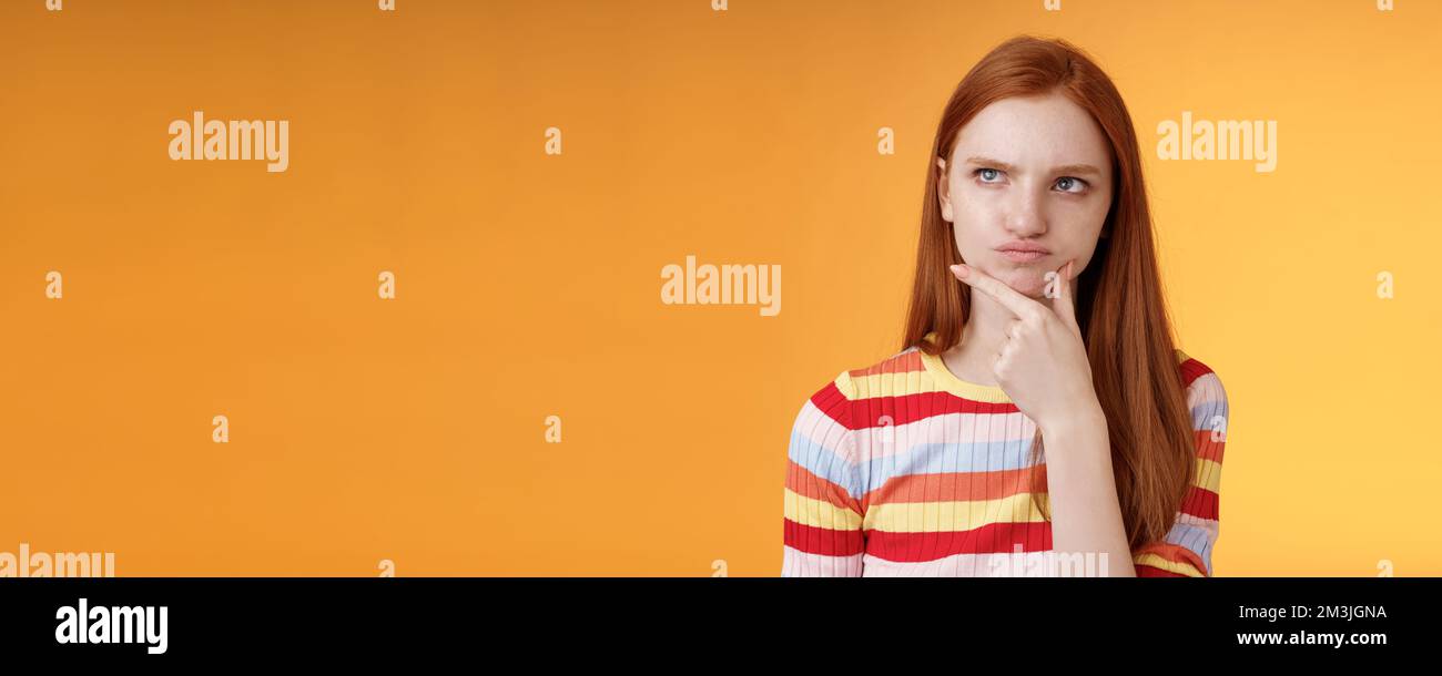 Perplexed hesitant serious-looking ginger girl blue eyes weihing ...