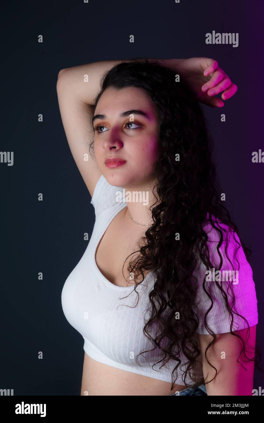Profile of young woman wearing white shirt with one hand on her head ...