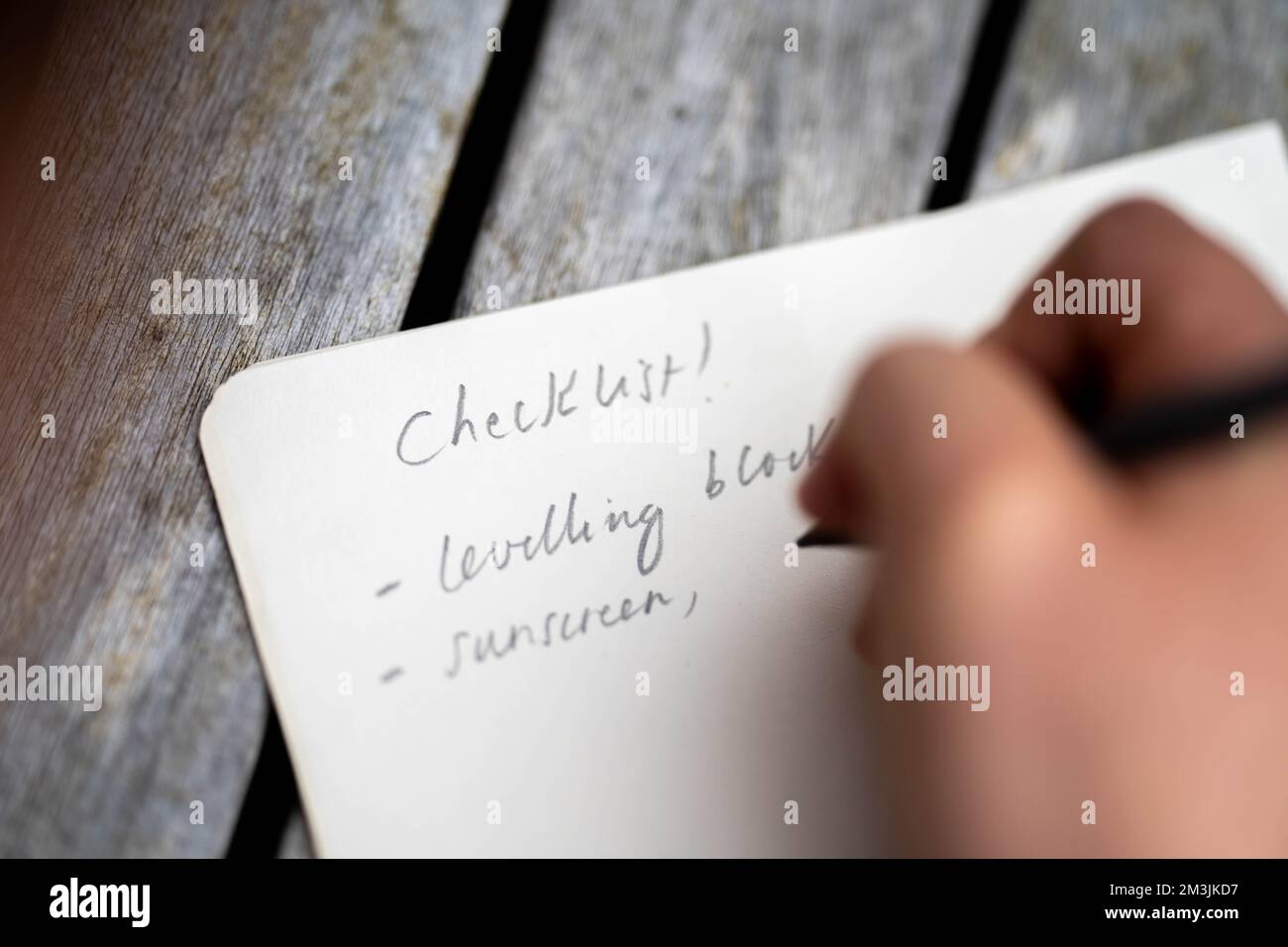 gril writing a camping list in a piece of paper. writing a check list ...