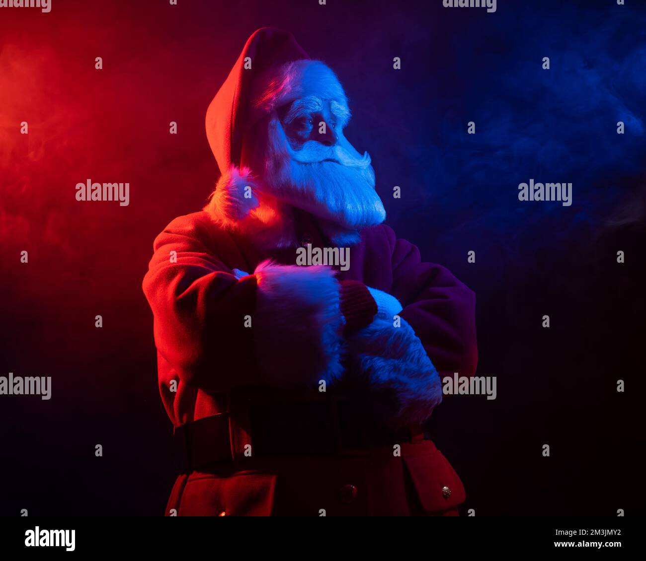 Santa Claus stands with his arms crossed on his chest in blue red neon ...