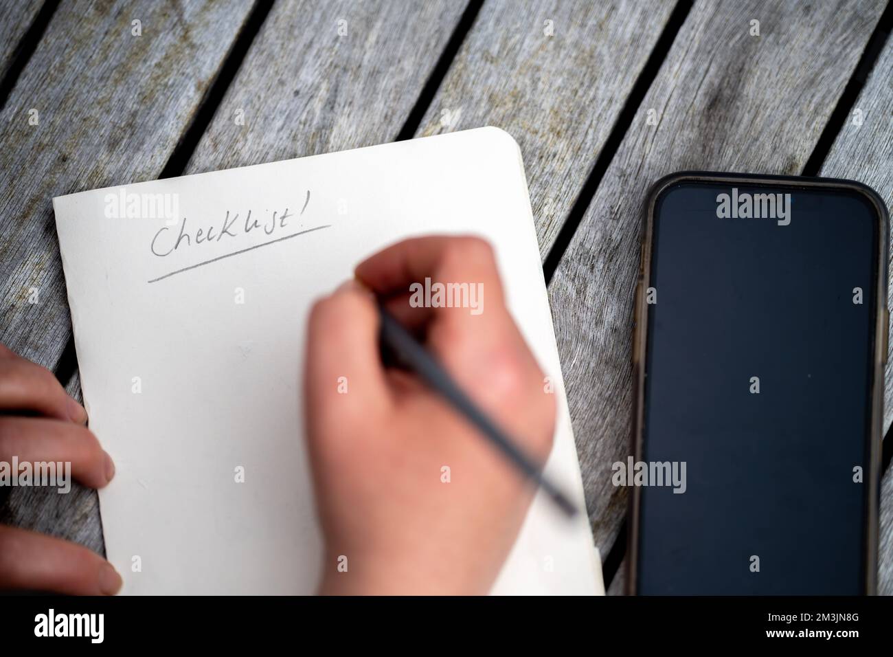 gril writing a camping list in a piece of paper. writing a check list ...