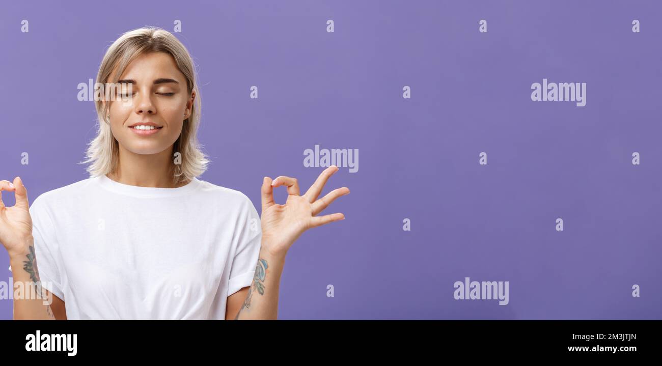 Peaceful calm good-looking female blonde in white t-shirt closing eyes ...