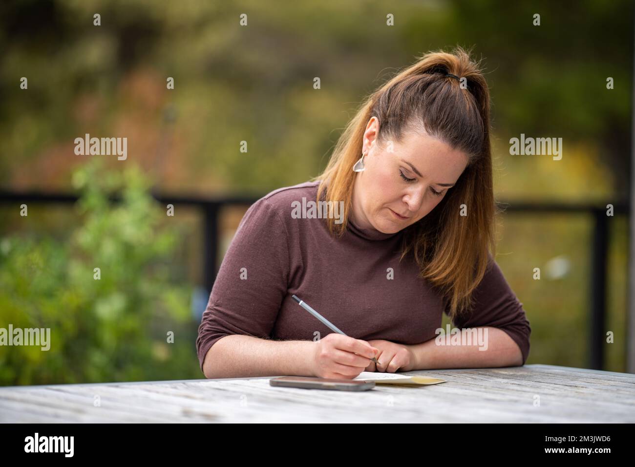 gril writing a camping list in a piece of paper. writing a check list ...