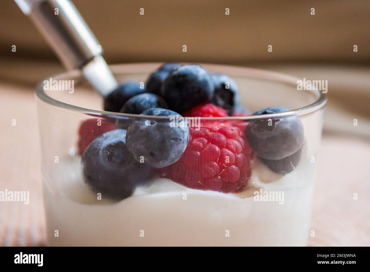 A closeup shot of glass cup of yogurt raspberry and blackberry against ...