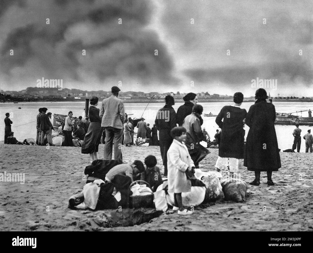 Photograph showing refugees from the city of Irun standing on the beach ...