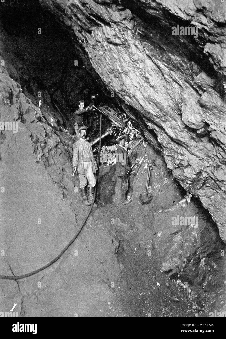 Photograph showing three miners using an air rock-drill in part of the ...
