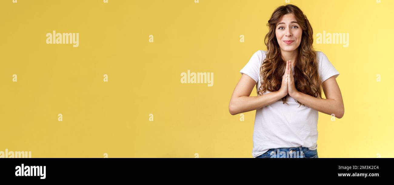 Cute hopeful young caucasian girl stooping hold hands pray smiling hope ...