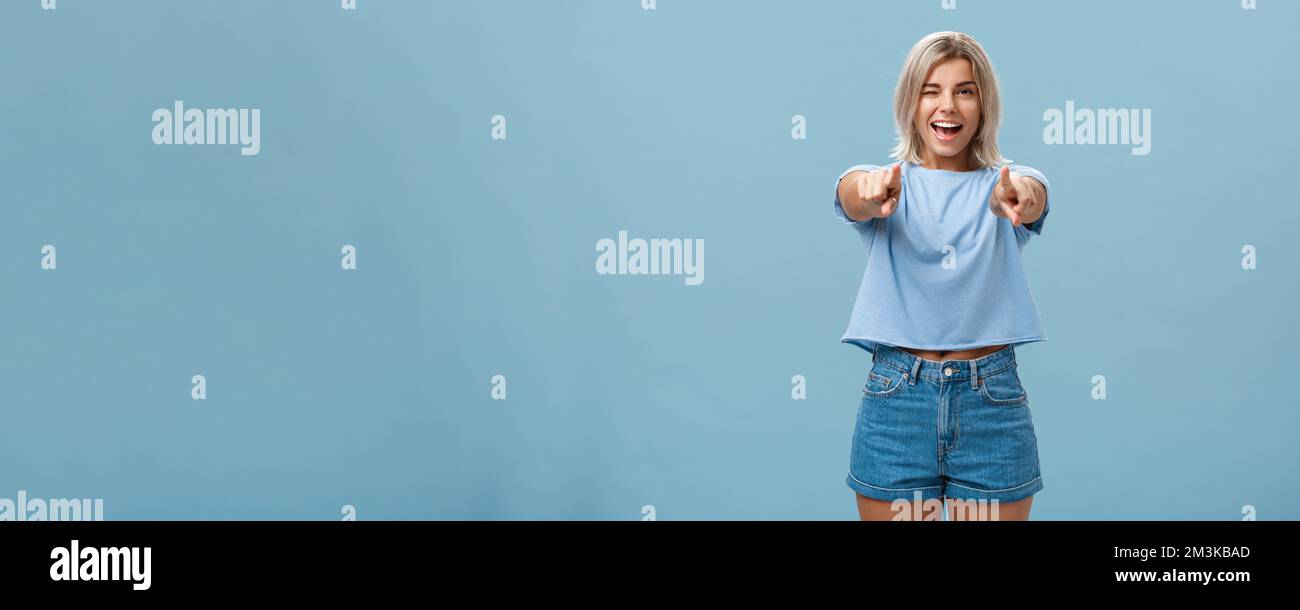 Happy enthusiastic stylish blonde female with tattoos pointing at ...