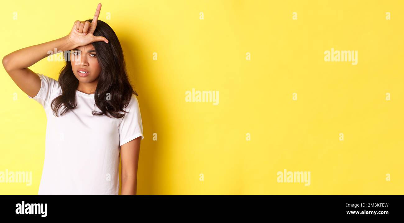 Image of sad african-american girl showing loser sign on forehead ...
