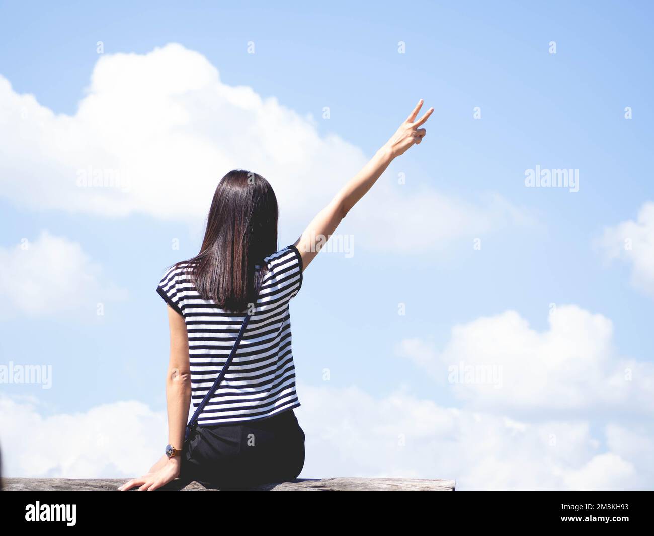 A woman with her back raised two fingers against the bright sky Stock ...