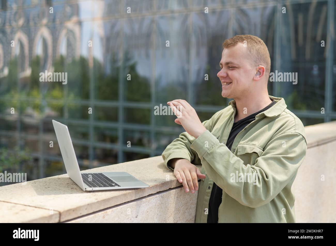 Caucasian man communicates in sign language via video link on laptop ...