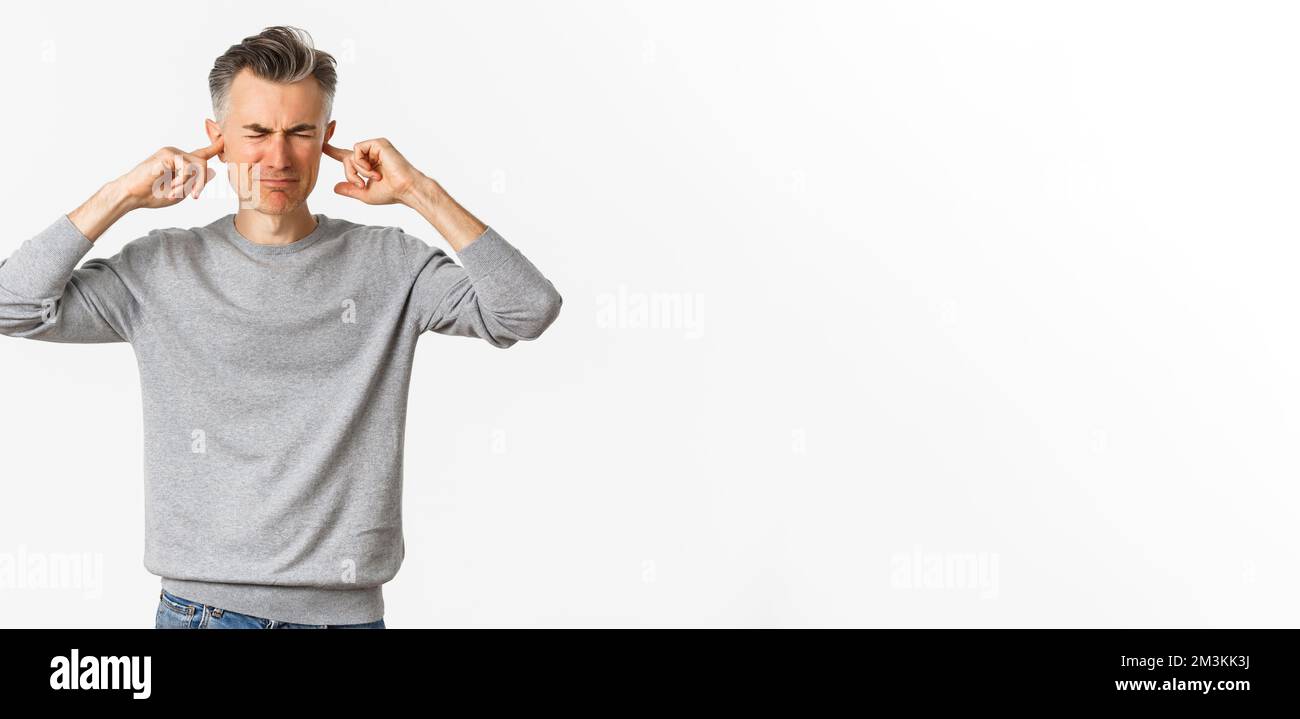Portrait of annoyed and distressed middle-aged man, grimacing from loud ...