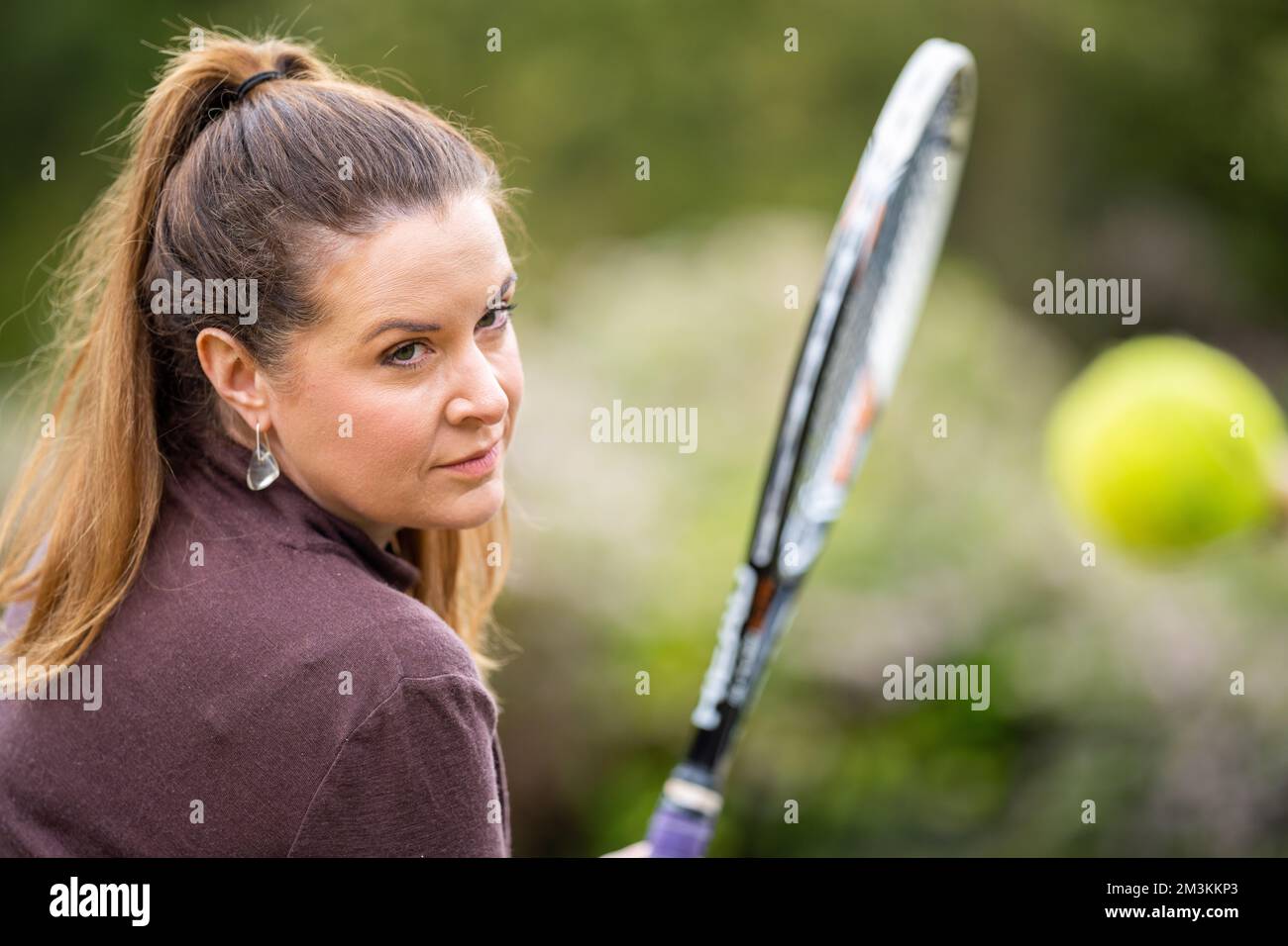 female tennis player practicing forehands and hitting tennis balls on a ...