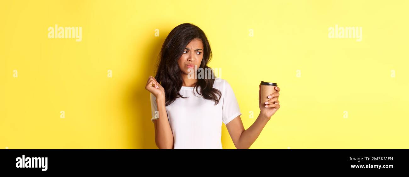 Portrait of african-american girl looking disappointed at cup, dont ...