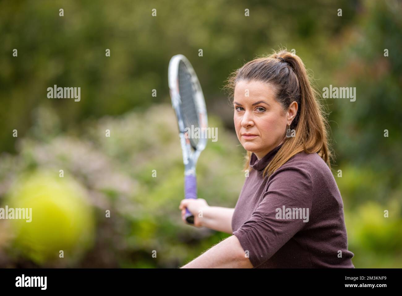 female tennis player practicing forehands and hitting tennis balls on a ...