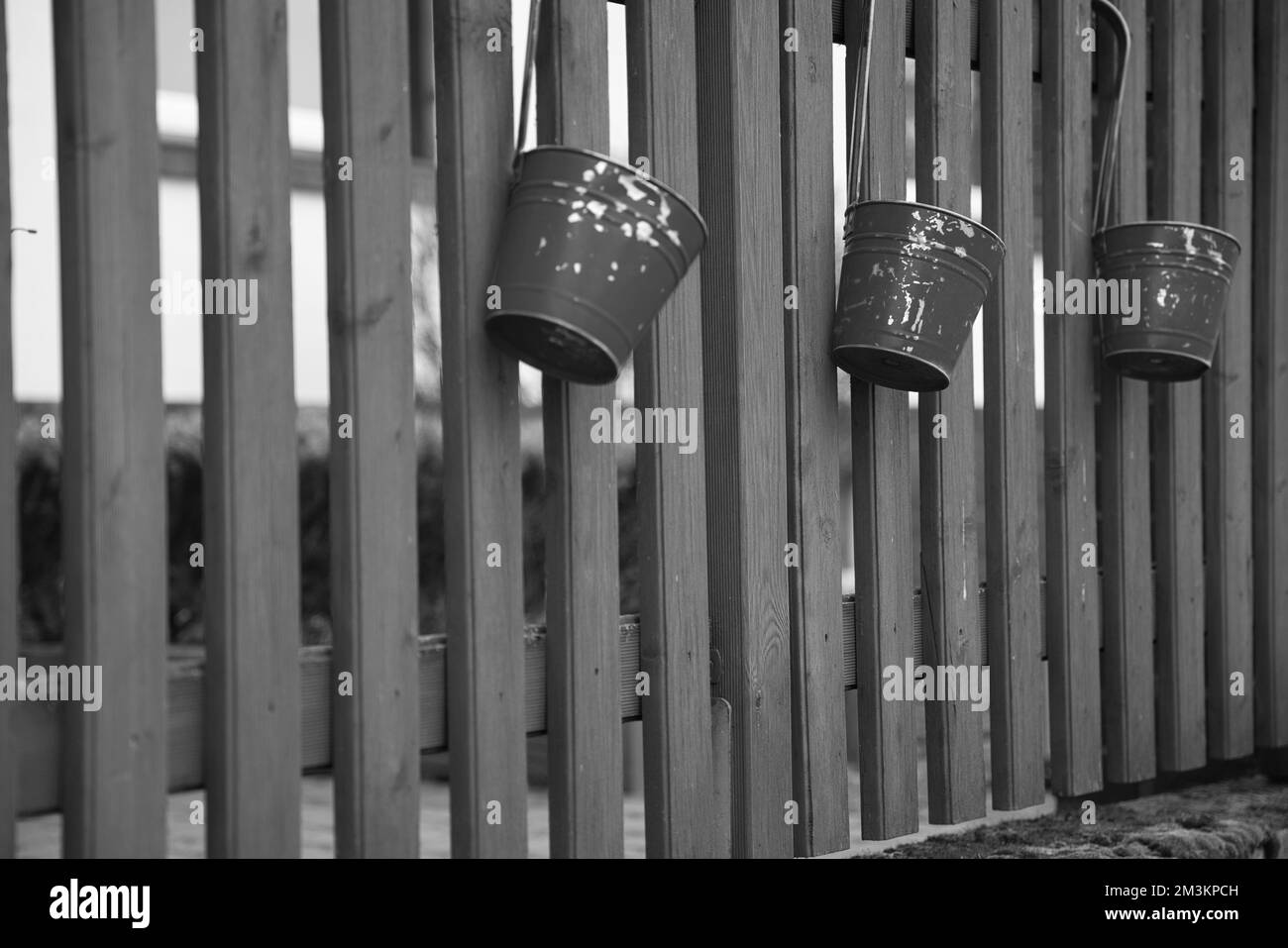 A grayscale of buckets hanging from a wooden fence Stock Photo - Alamy