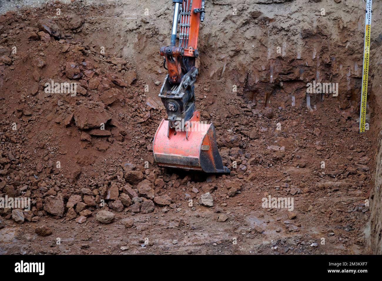 digger digging a large hole for a pool and tape measure to test the ...