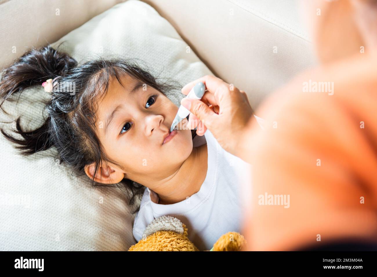Mother checking temperature of her sick daughter with thermometer in mouth Stock Photo - Alamy