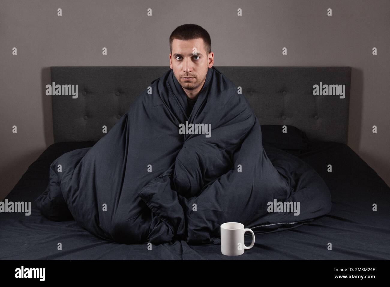 To feel bad. Sick guy with fever, drinking hot healing tea and touching ...