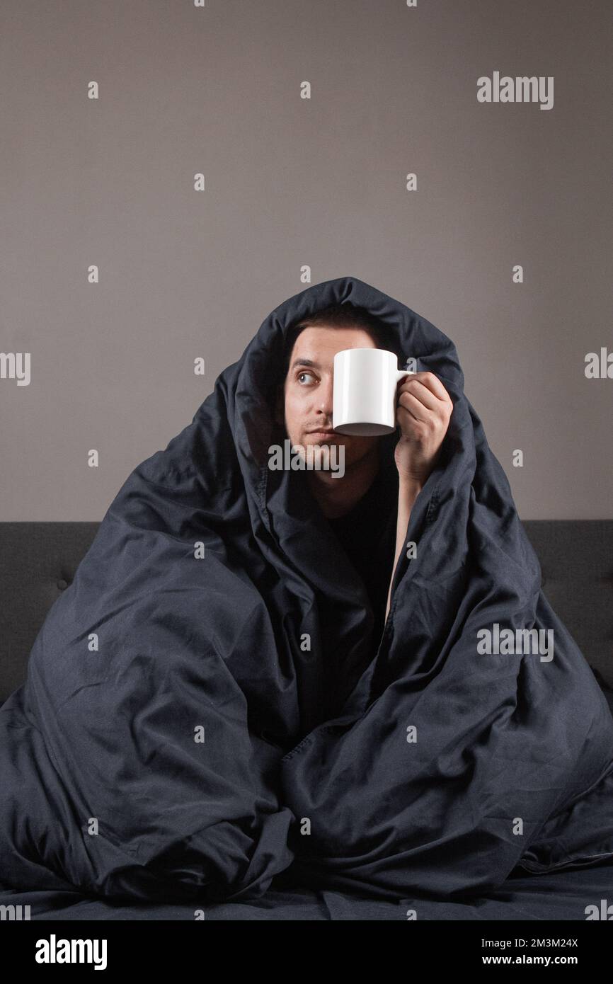 To feel bad. Sick guy with fever, drinking hot healing tea and touching ...